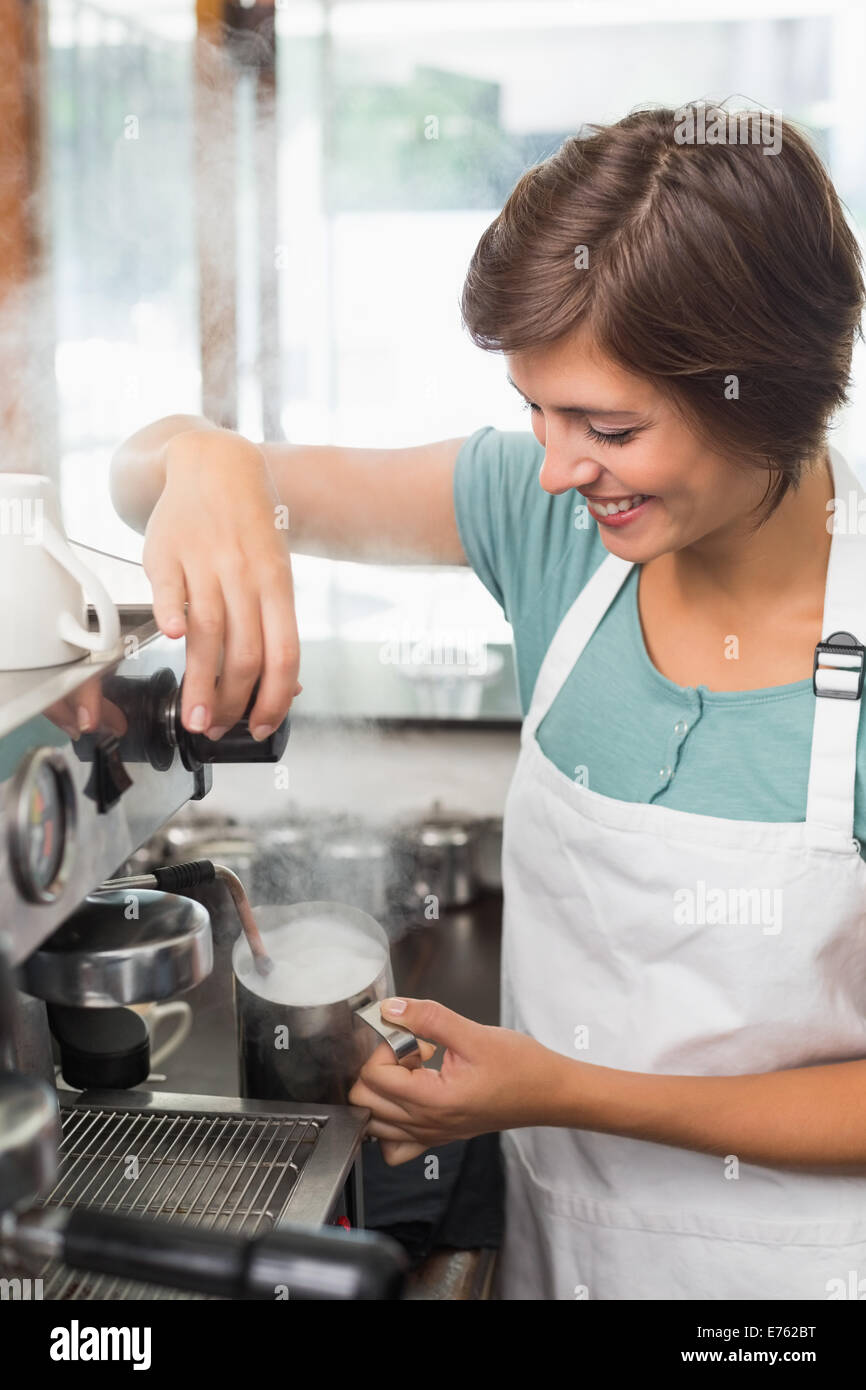 Pretty barista steaming jug of milk at coffee machine Stock Photo - Alamy