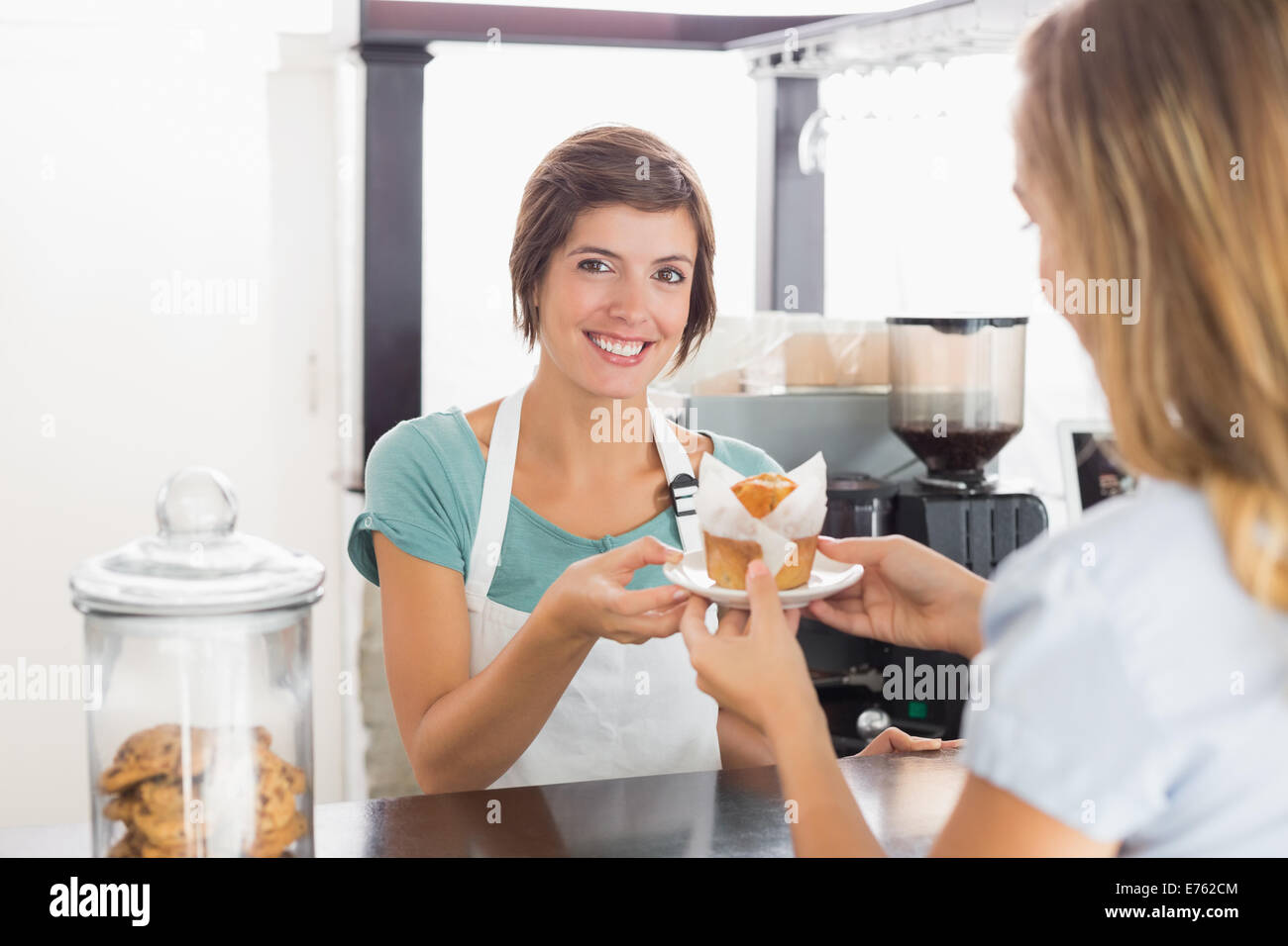 Pretty waitress serving muffin to customer Stock Photo - Alamy