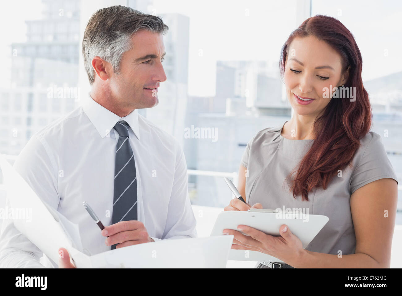 Business people comparing work notes Stock Photo - Alamy