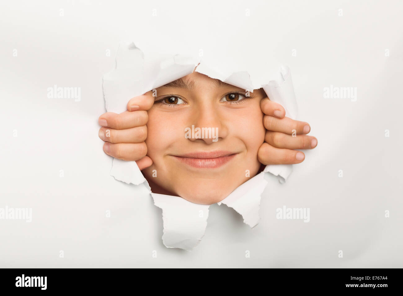 Cute little girl peeking through paper Stock Photo - Alamy