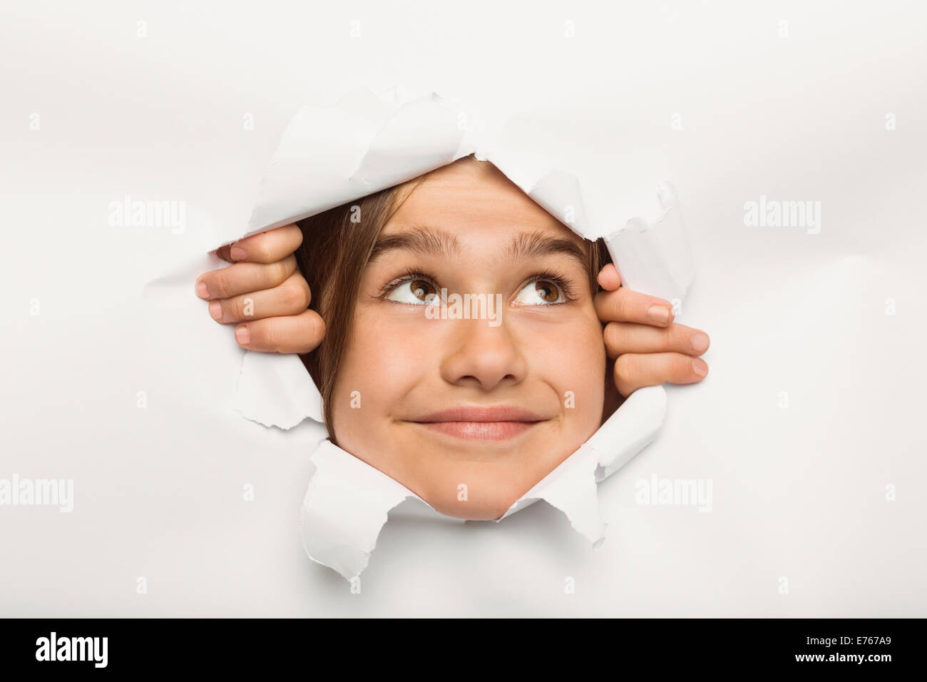 Cute little girl peeking through paper Stock Photo - Alamy