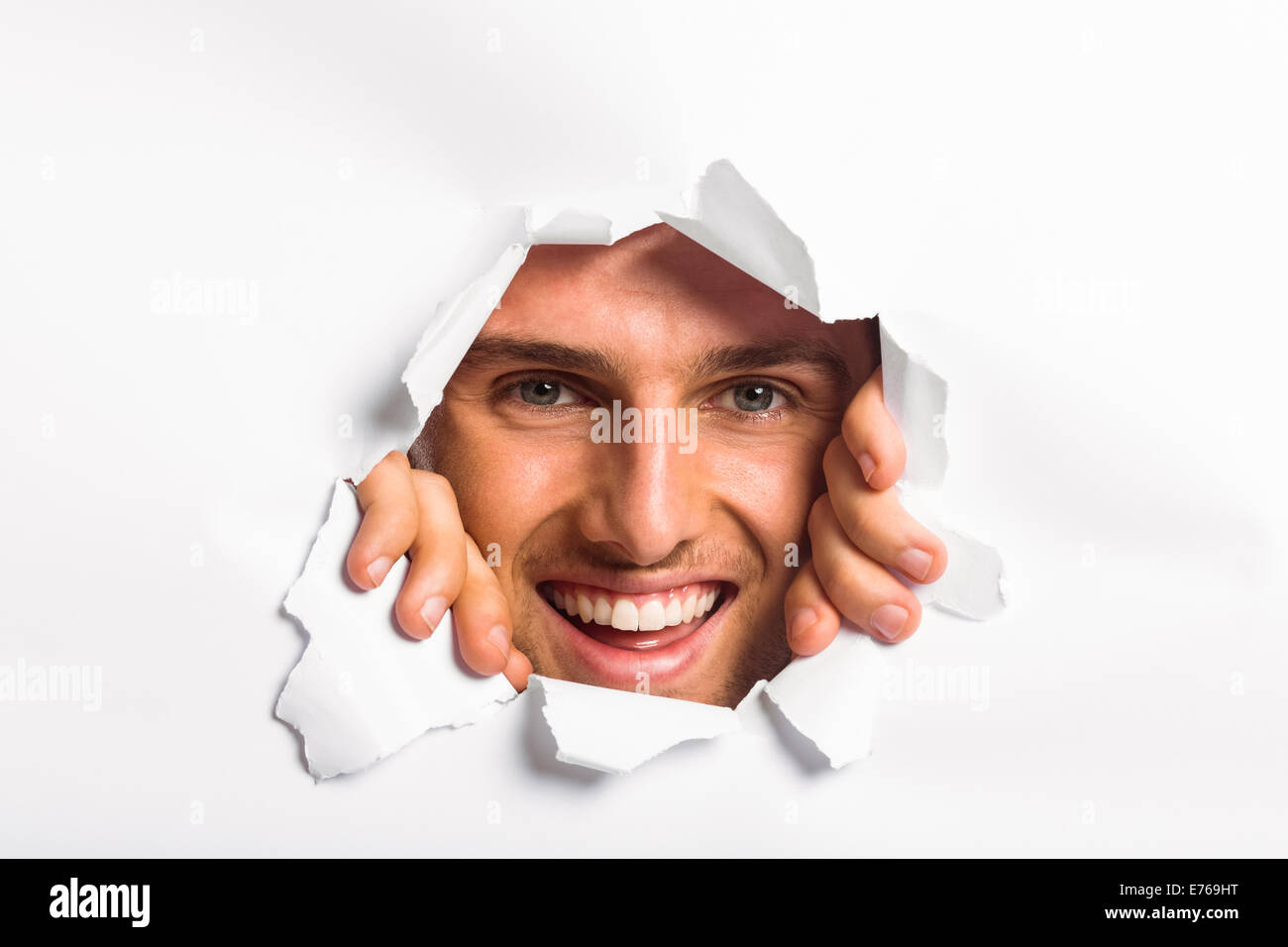 Young man looking through paper rip Stock Photo - Alamy