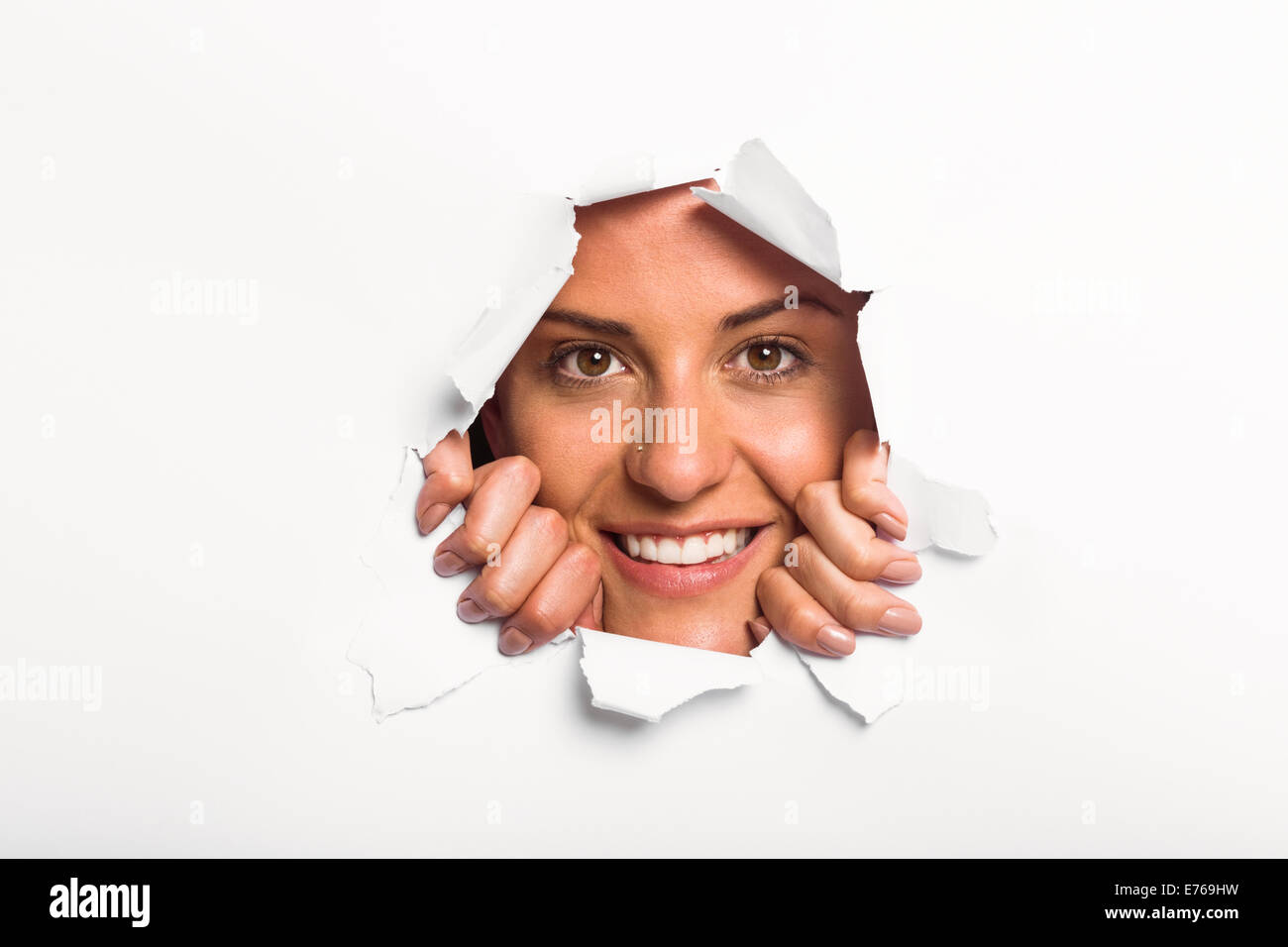 Young woman looking through paper rip Stock Photo - Alamy