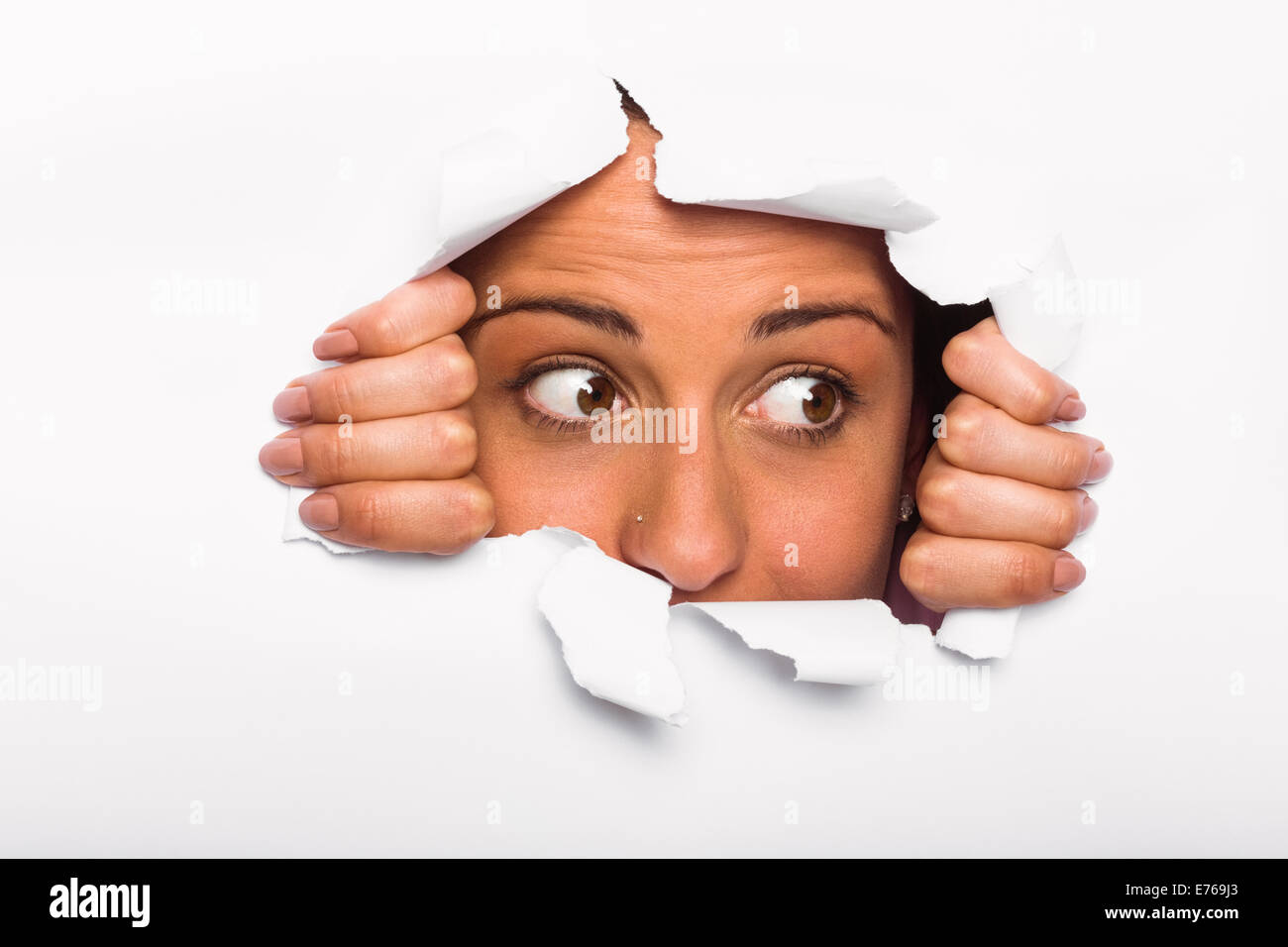 Young woman looking through paper rip Stock Photo - Alamy