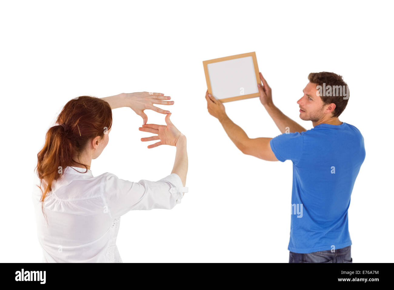 Couple deciding to hang picture Stock Photo - Alamy