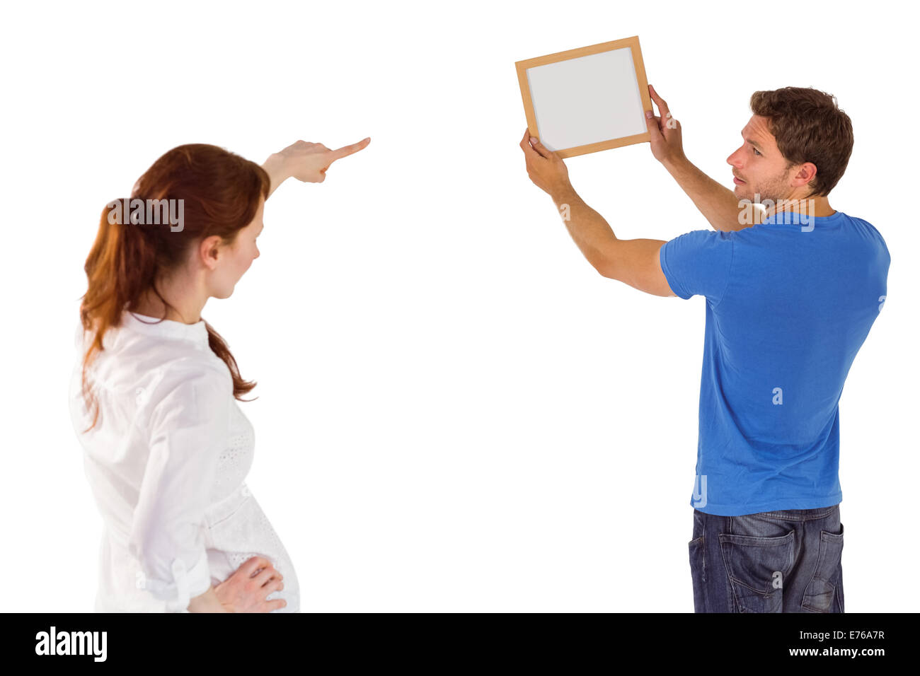 Couple deciding to hang picture Stock Photo - Alamy