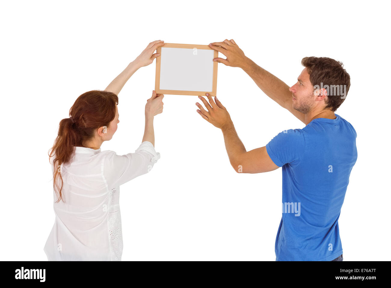 Couple deciding to hang picture Stock Photo - Alamy