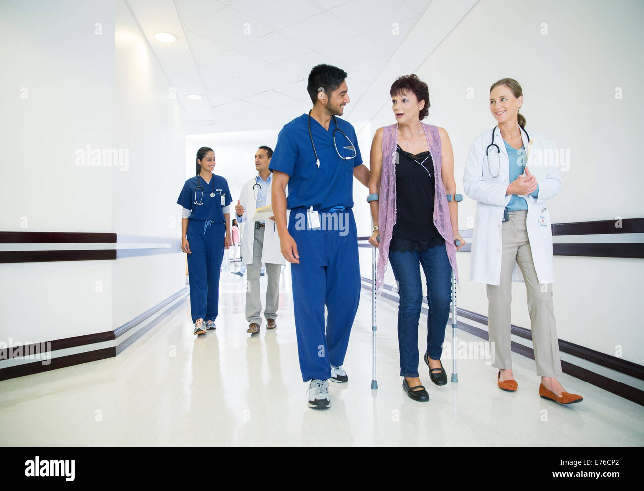 Doctor and nurse walking patient down hospital hallway Stock Photo - Alamy