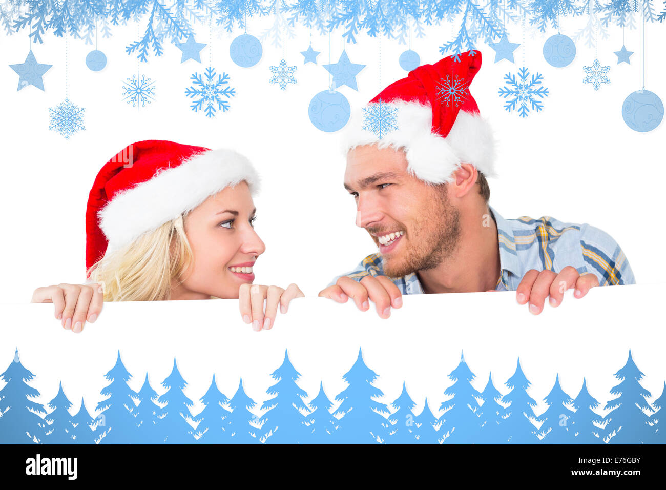 Composite image of festive couple smiling from behind poster Stock ...