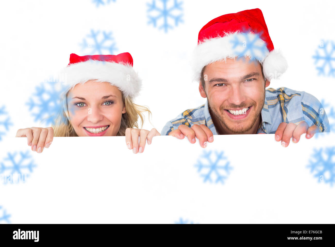 Composite image of festive couple smiling from behind poster Stock ...