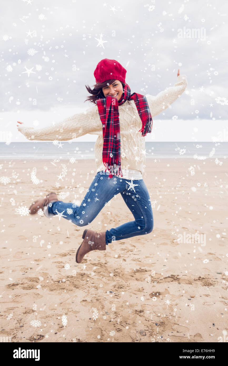 Composite image of woman in stylish warm clothing jumping at beach ...