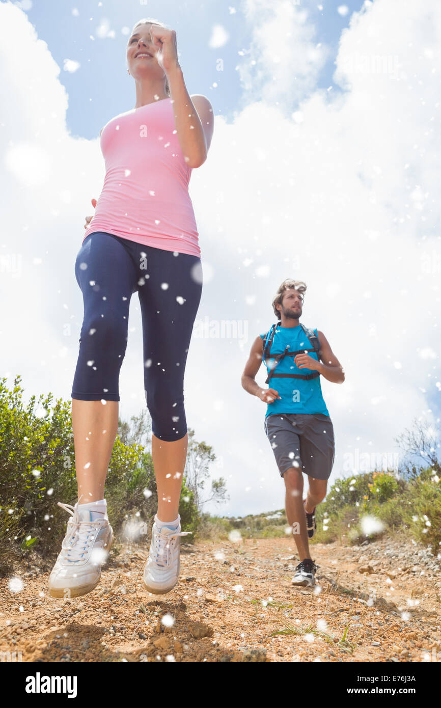 Composite image of fit attractive couple jogging down mountain trail ...