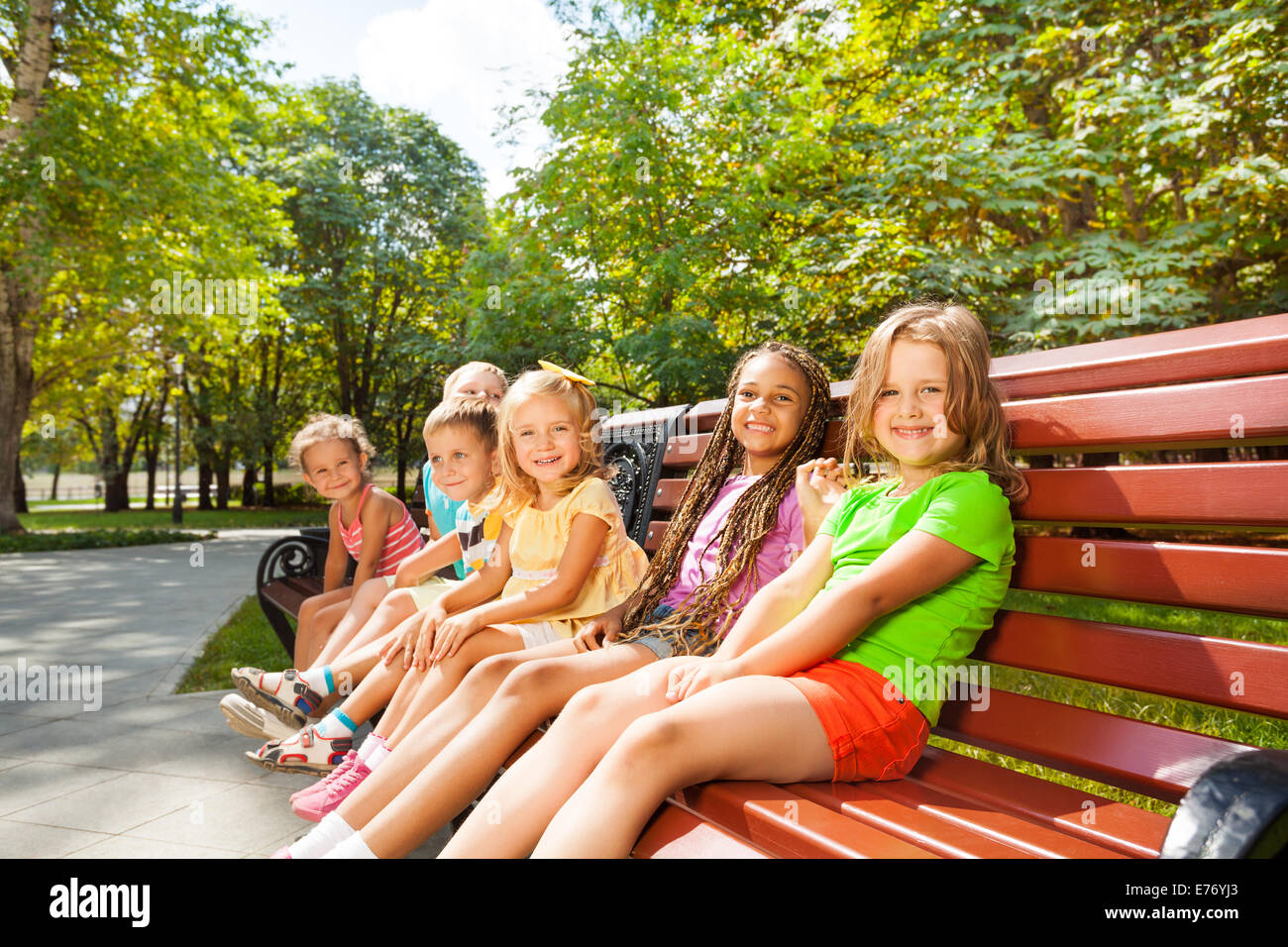 Boys and girls sitting on summer bench in park Stock Photo - Alamy