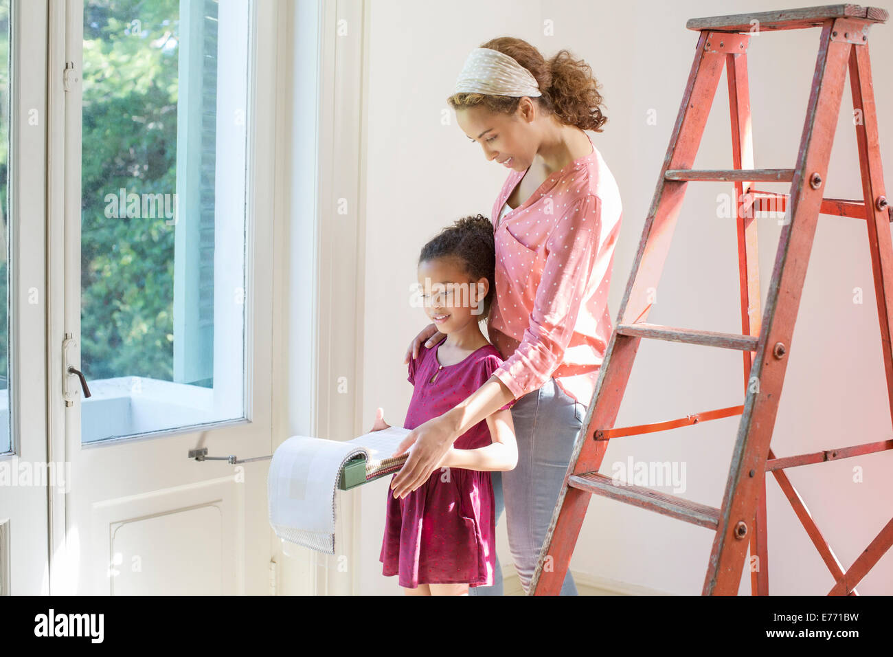Mother and daughter looking through binder together Stock Photo - Alamy