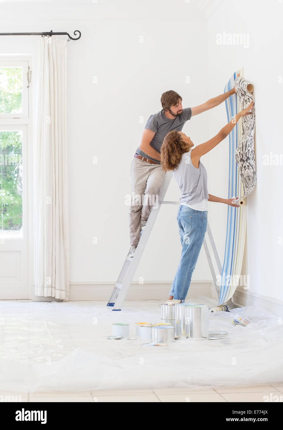 Couple hanging wallpaper together Stock Photo - Alamy