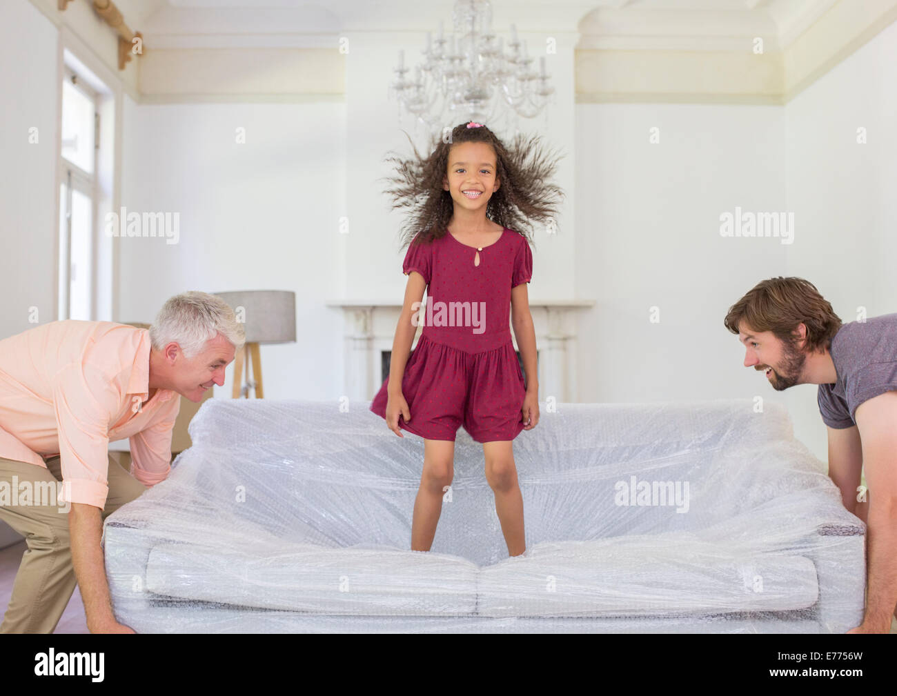 Family lifting couch with young girl standing on top Stock Photo - Alamy