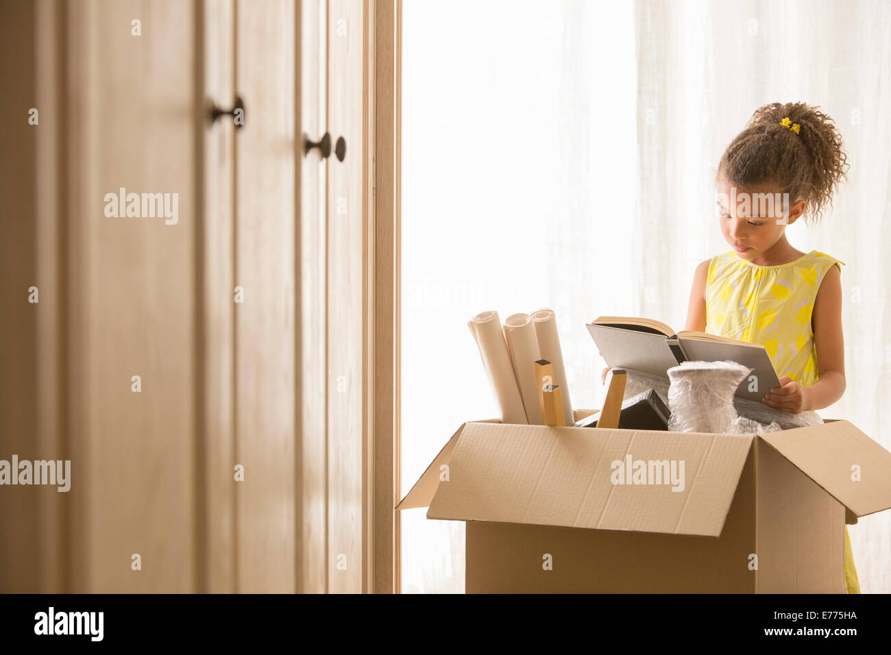 Young girl reading book near moving box Stock Photo - Alamy