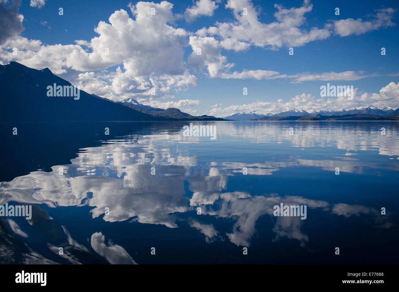 The tranquil lake reflects the sky, creating a mirrored effect on the ...