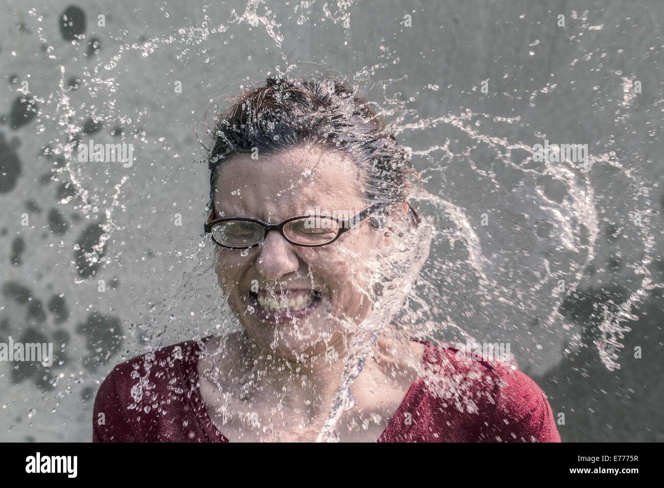 A woman is surprised by a splash of water, wearing spectacles and ...