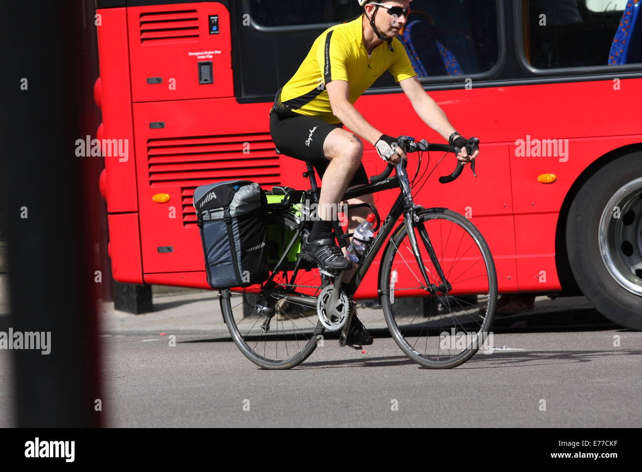 A cyclist riding alongside a red London bus Stock Photo - Alamy