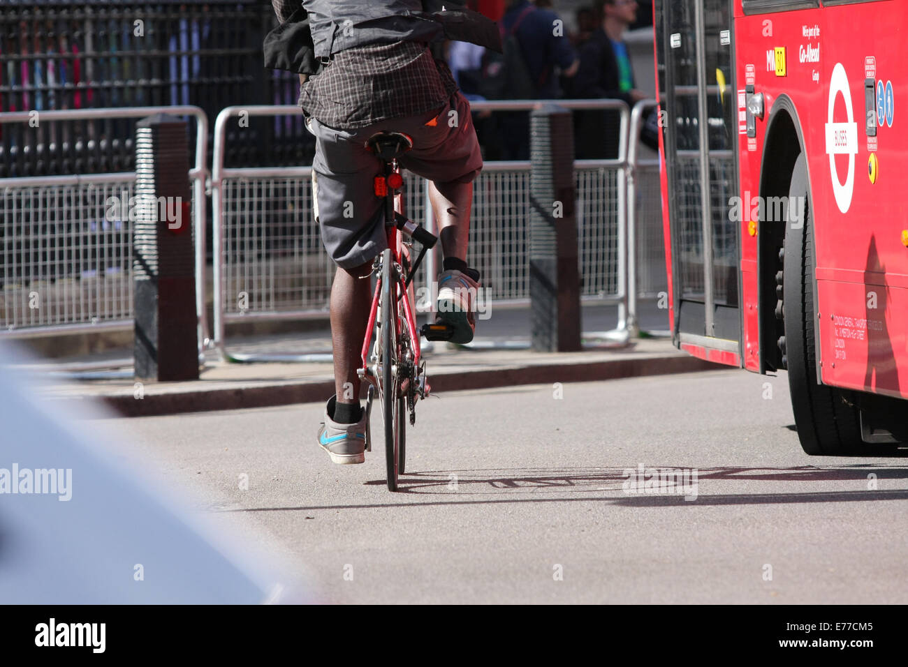 A cyclist and red London bus turning right on a road in London Stock ...