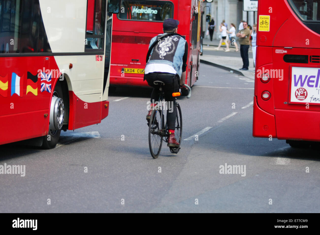 A cyclist traveling amongst red London buses, in London Stock Photo - Alamy