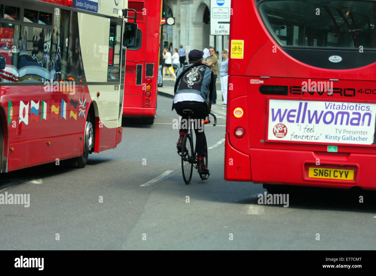 A cyclist traveling amongst red London buses, in London Stock Photo - Alamy