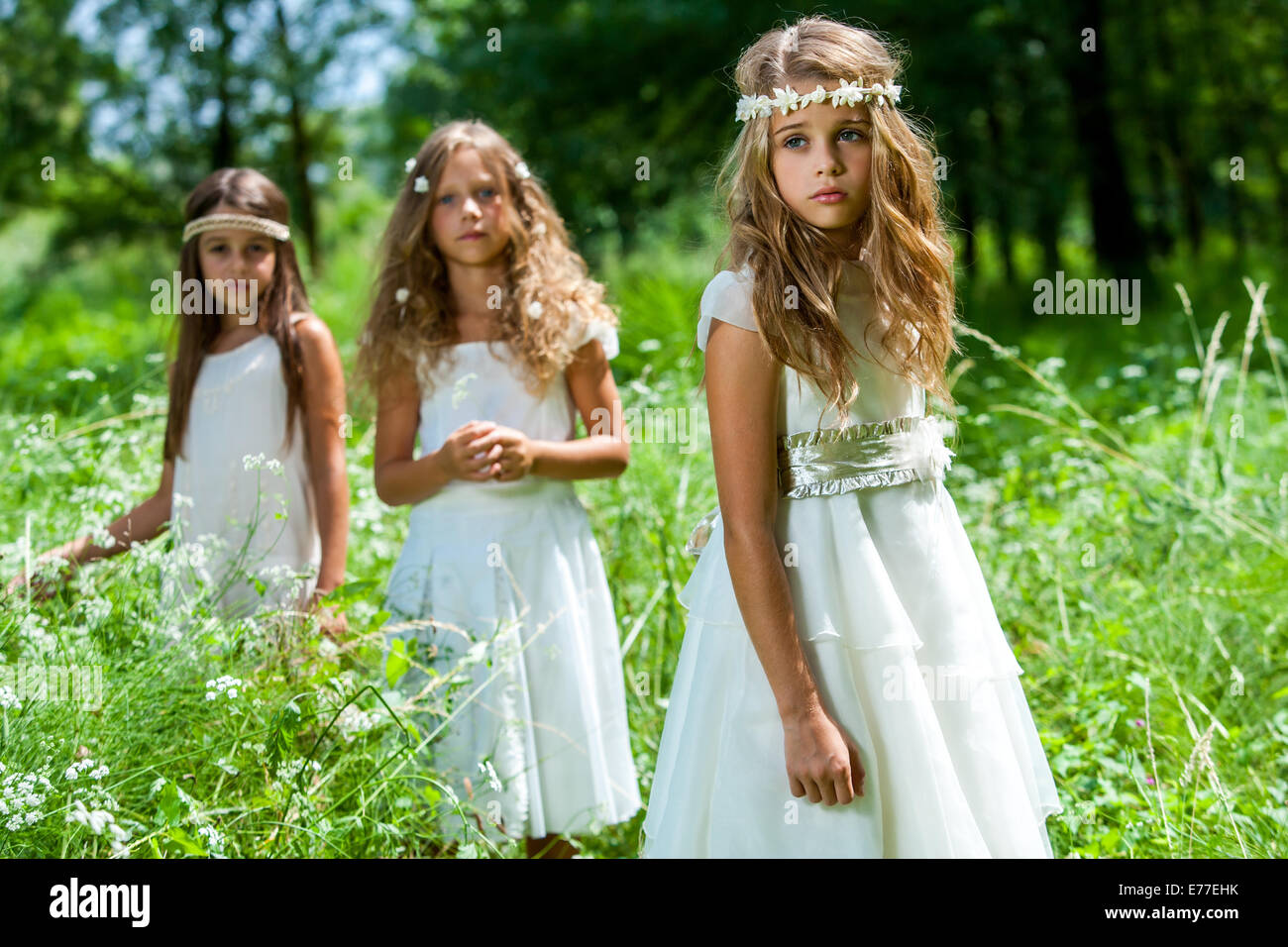 Portrait of three girl friends wearing white dresses in woods Stock ...