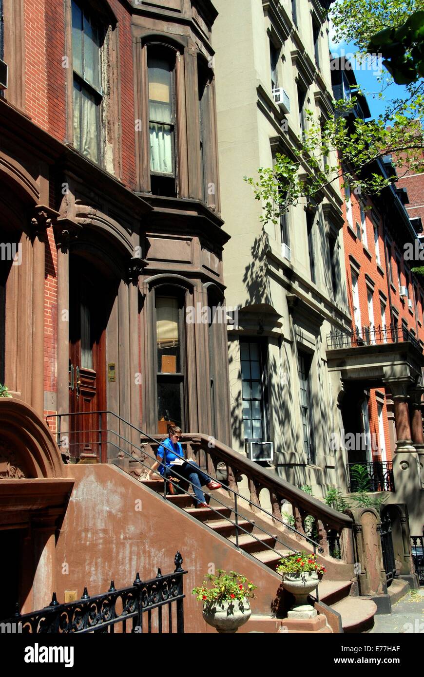 BROOKLYN HEIGHTS, NY: Woman reading on the stoop of a classic 19th ...