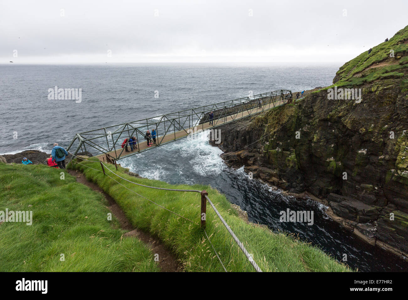 Hikers crossing the bridge between Mykines and Mykineshólmur. Faroe ...