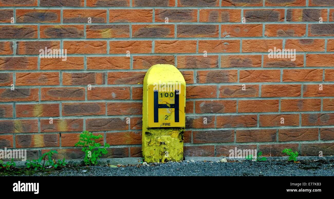 A yellow fire hydrant sign against a brick wall england uk Stock Photo ...