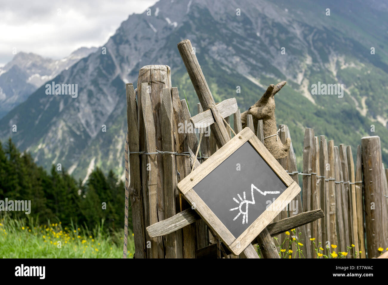 Wooden palisade with chalkboard hint panel in front of a mountain ...