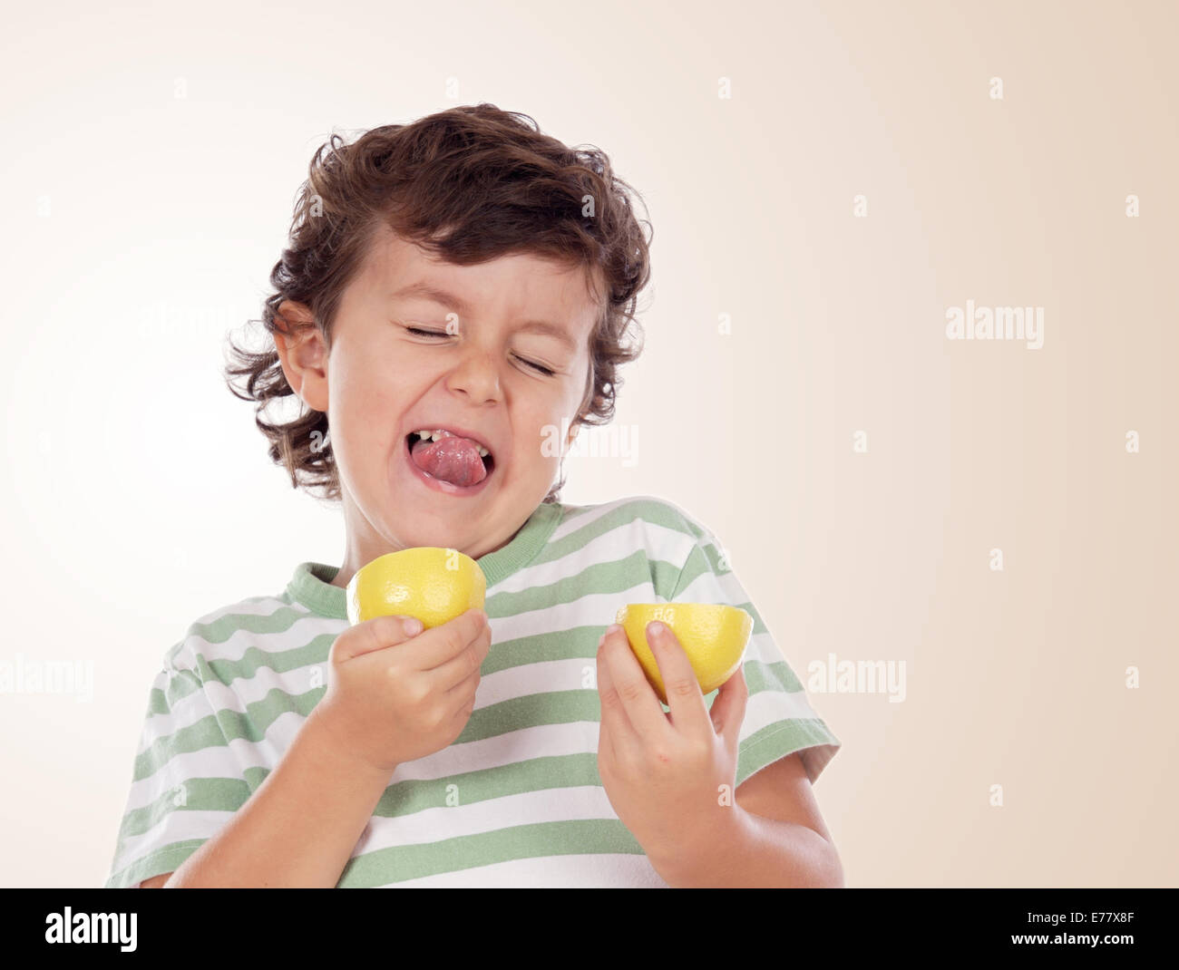 Cute boy eating lemon isolated on a orange background Stock Photo - Alamy