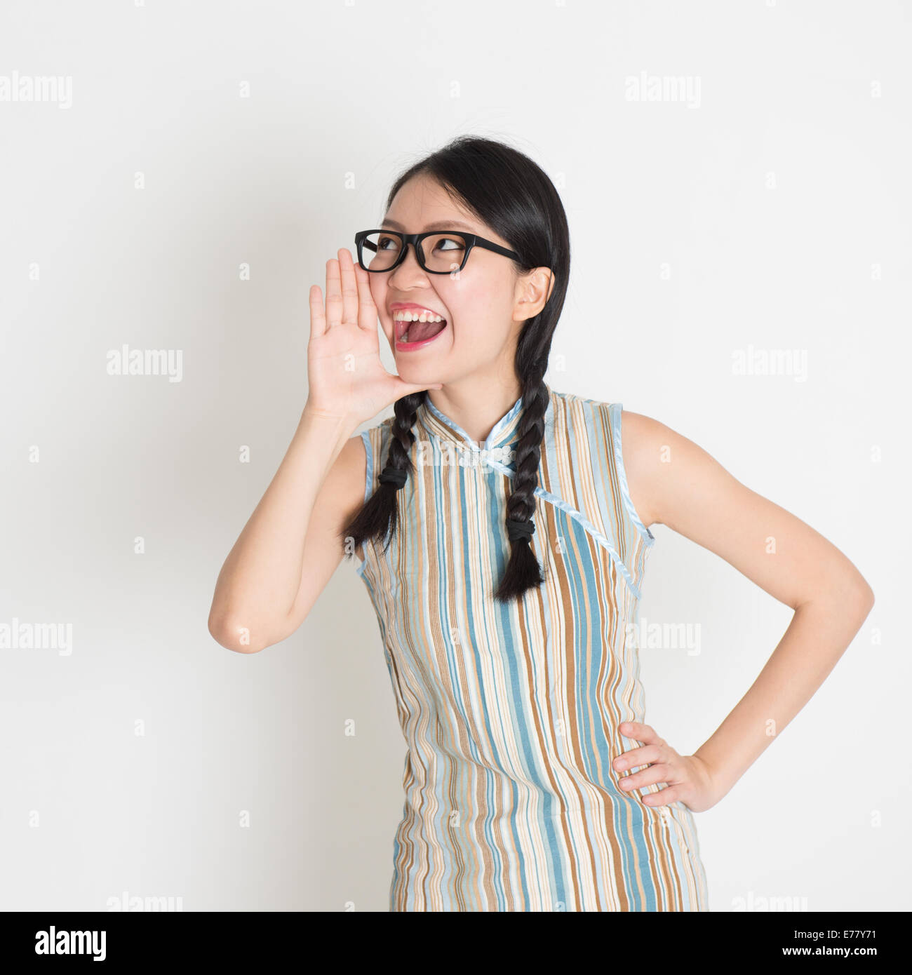 Portrait of Asian Chinese female shouting loud, hand next to the mouth ...