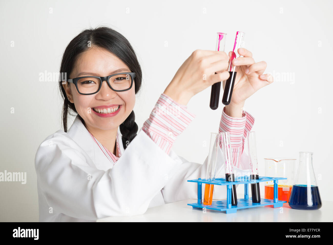 Asian lab worker doing blood sample test analysis, on plain background ...