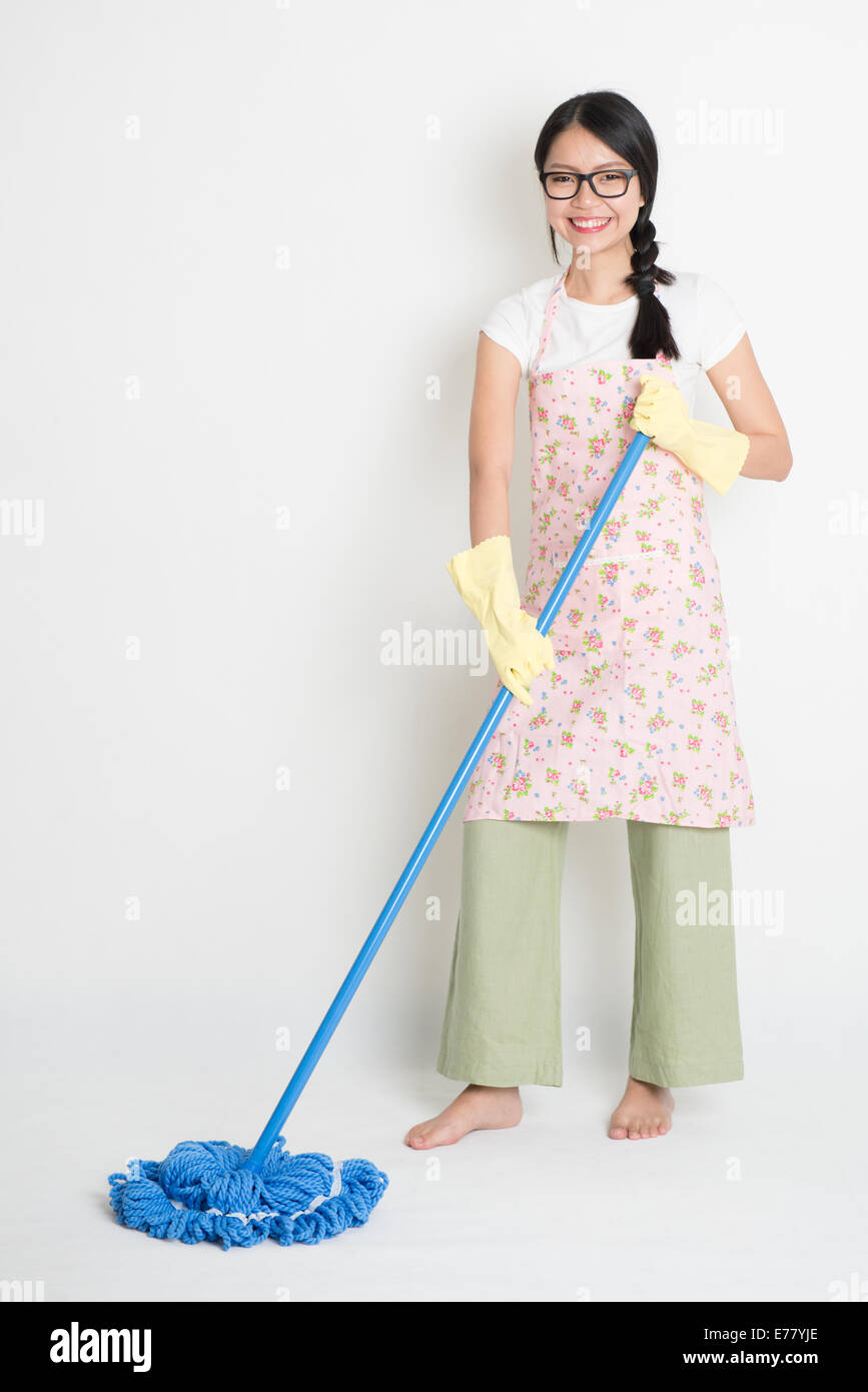 Full length Asian Chinese girl housekeeping, mopping floor on plain ...