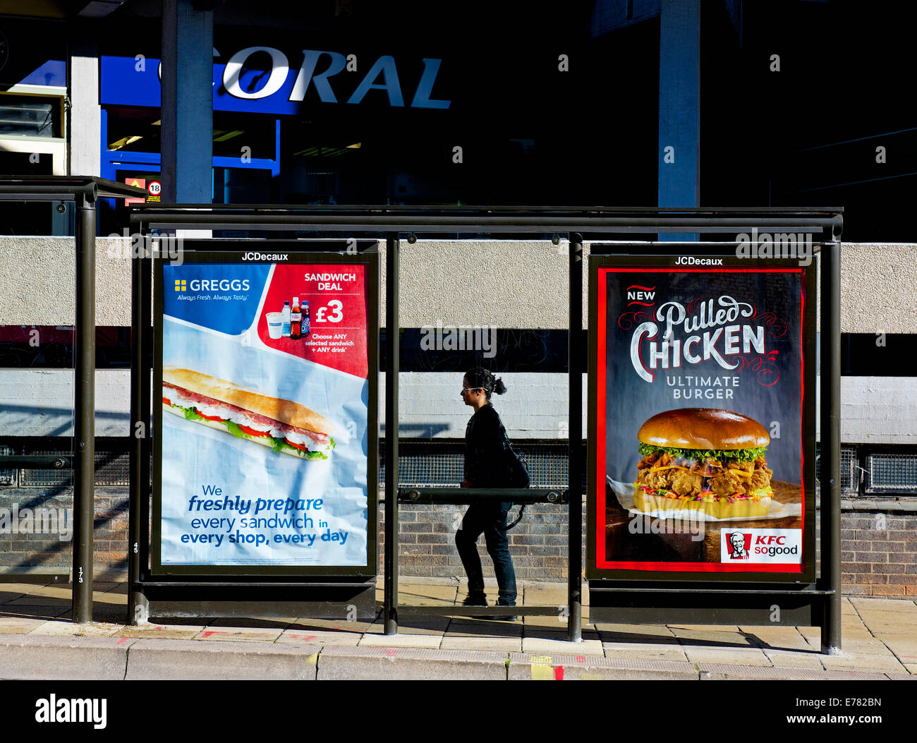 Young woman walking past bus shelter, Stonebow, York, North Yorkshire ...