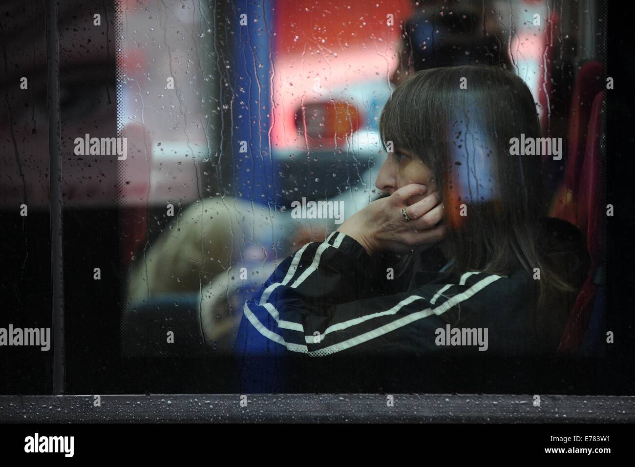 A depressed unhappy woman commuter sits on a bus during a rainy day ...