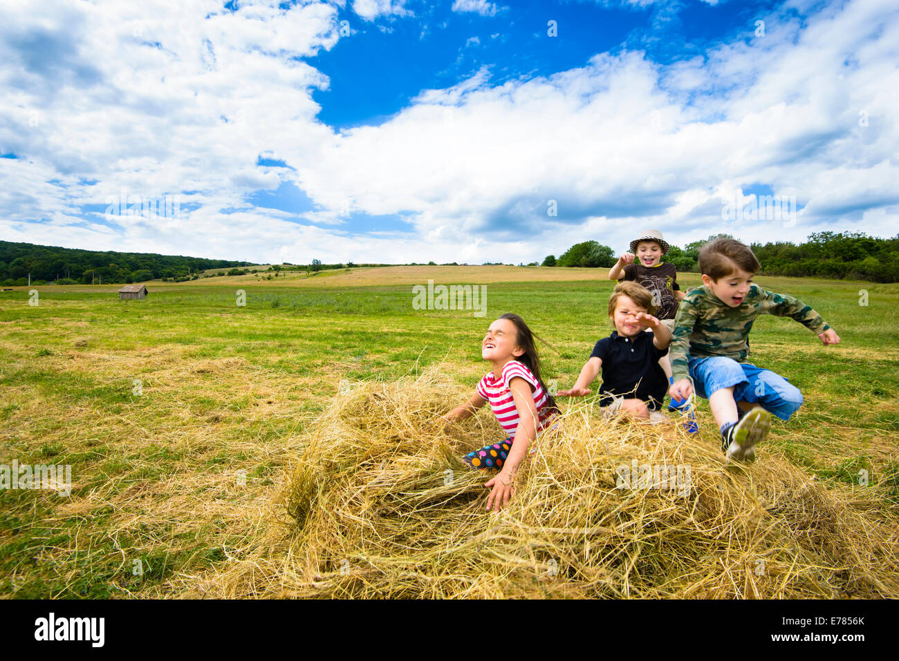 Kids running and jumping in a pile of straw, summer day Stock Photo - Alamy