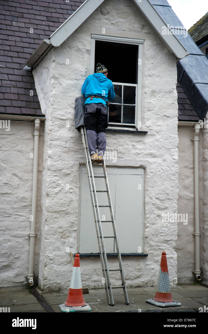 A workman up a ladder fixing window Stock Photo - Alamy