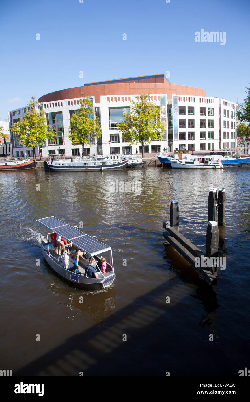small boat with solar panels in river amstel in front of opera house in ...