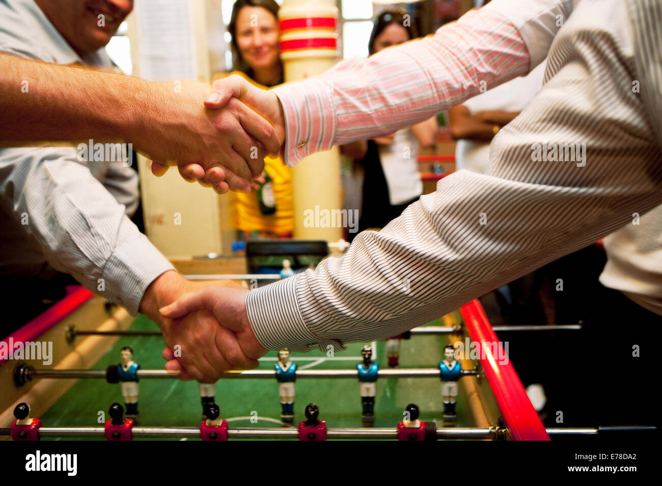 Four businessmen shake hands after an indoor table football game Stock ...