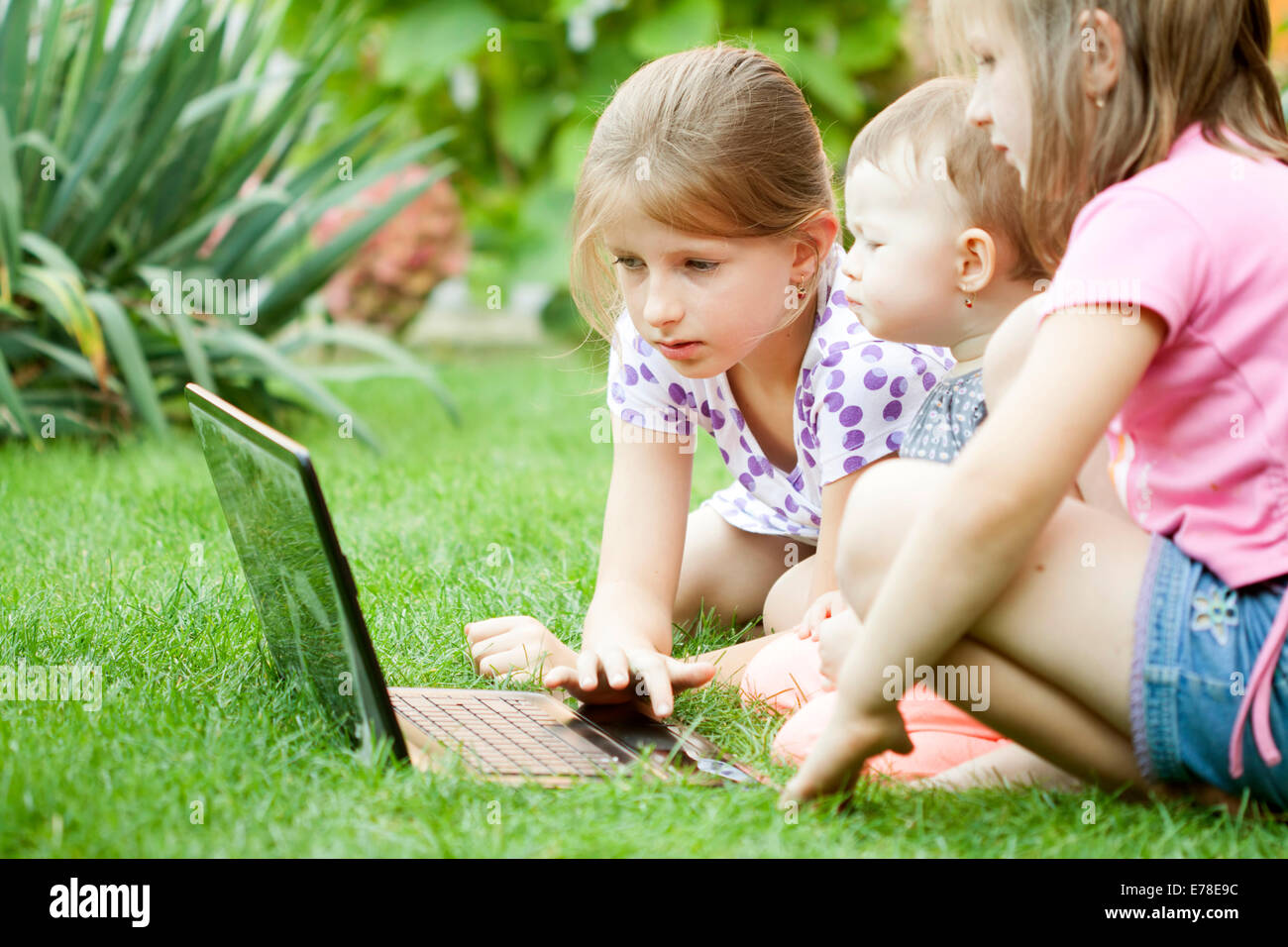 Curious kids with laptop computer laying in the grass Stock Photo - Alamy