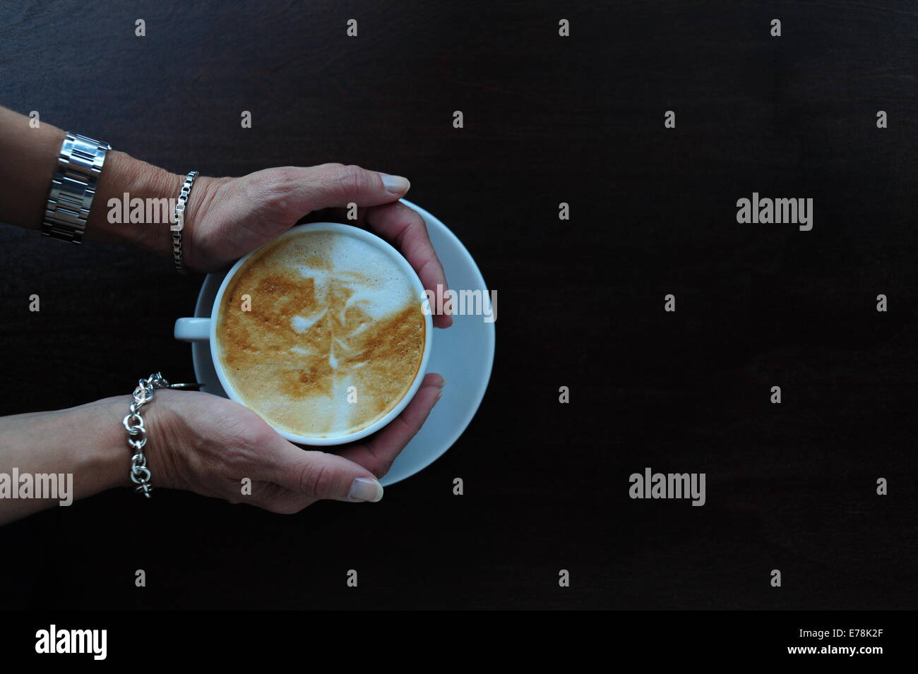 Mature woman in cafe holding a cup of coffee cappuccino over head view ...