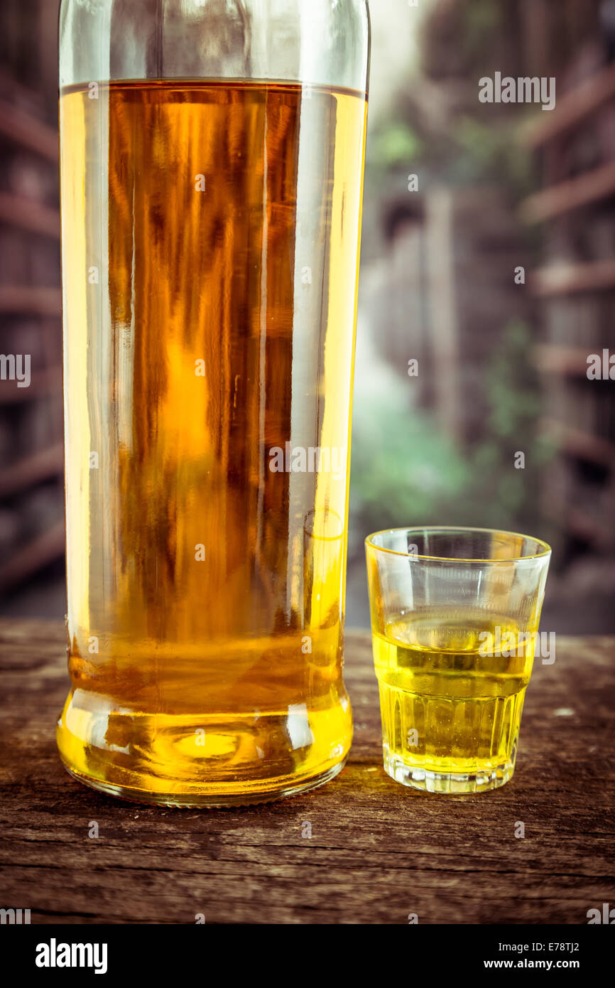 Bottle and glass shot with yellow liqour resembling whiskey, rum ...