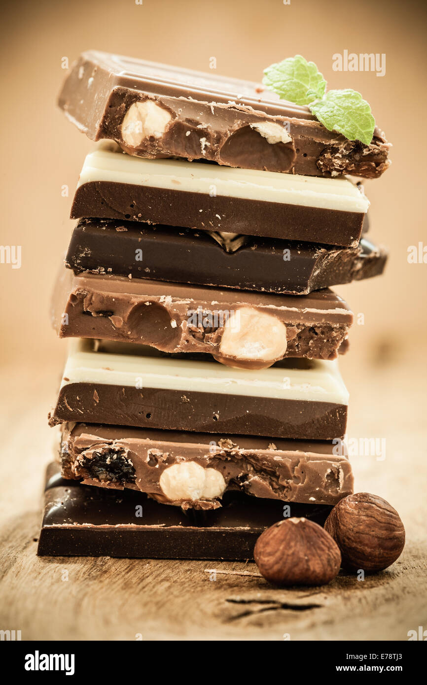 Closeup stack of different sorts chocolate pieces and hazelnuts ...