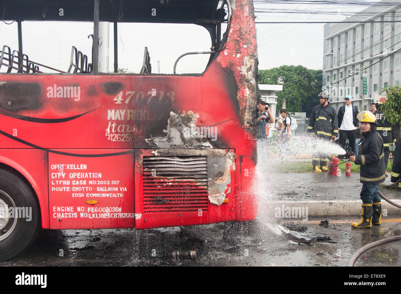 A firefighter douses water on the burned passenger bus along the ...