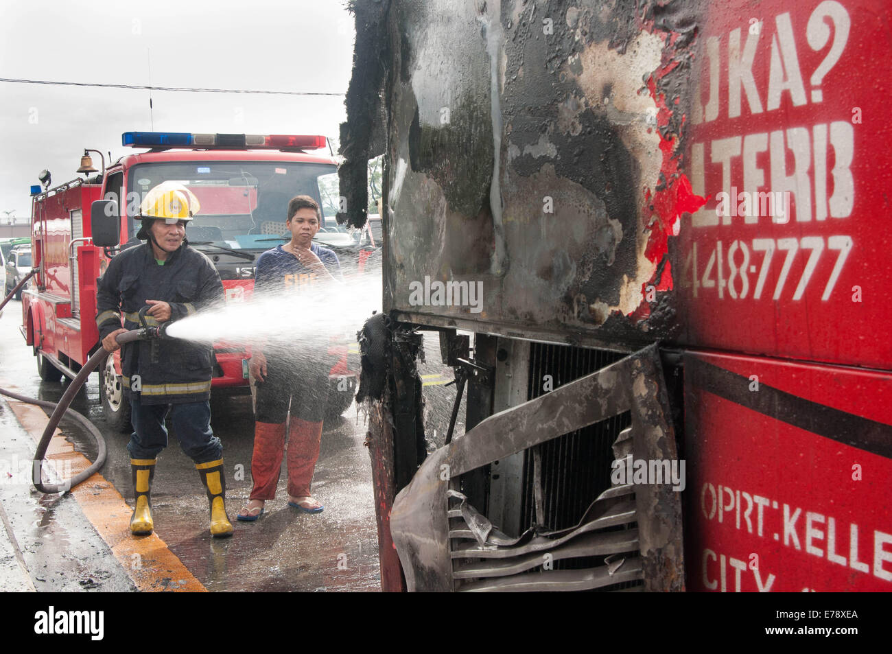 A firefighter douses water on the burned passenger bus along the ...