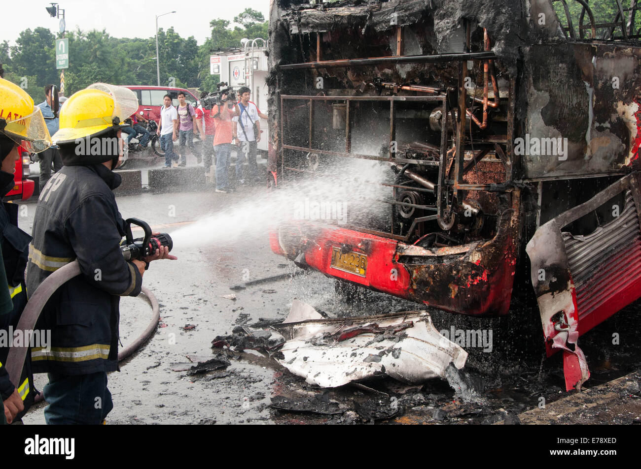 Firefighters douse water on the burned passenger bus along the ...