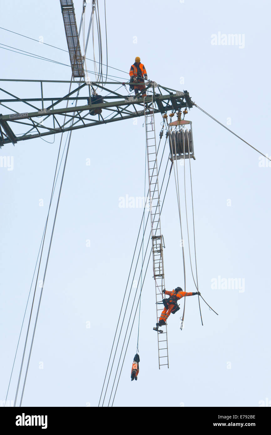 Overhead transmission cable installers installing insulated cable on ...